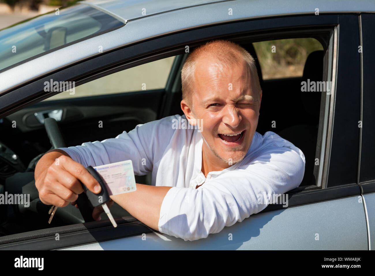 Portrait of an excited Caucasian male driver holding the keys of his ...