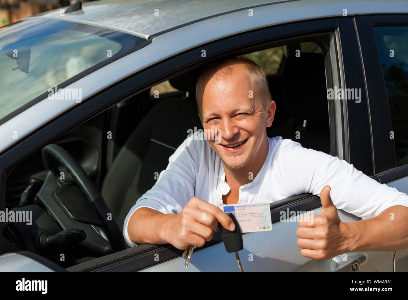 Portrait of an excited Caucasian male driver holding the keys of his ...
