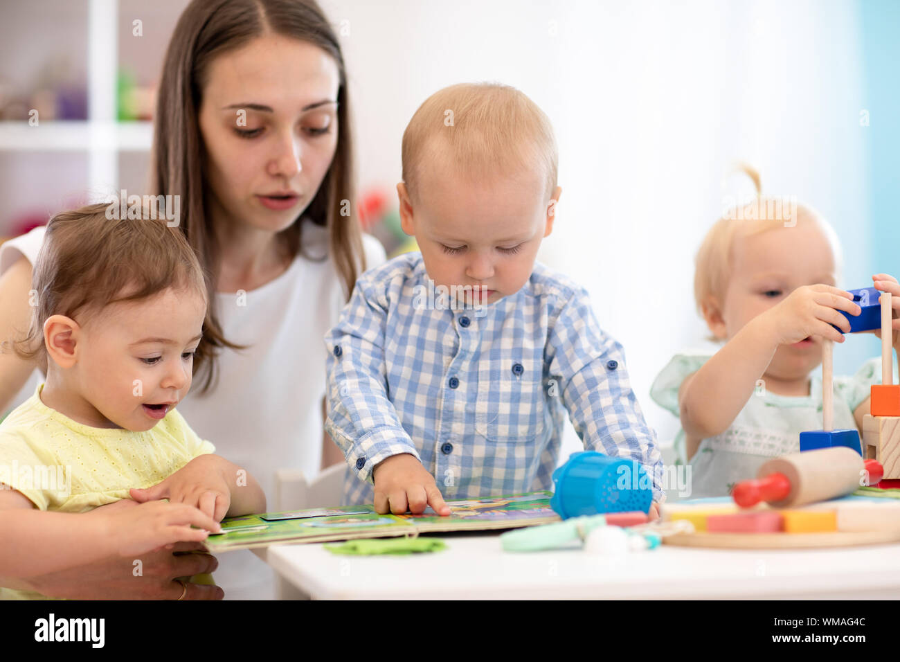 Adorable children learning book with their teacher, Nursery babies on ...