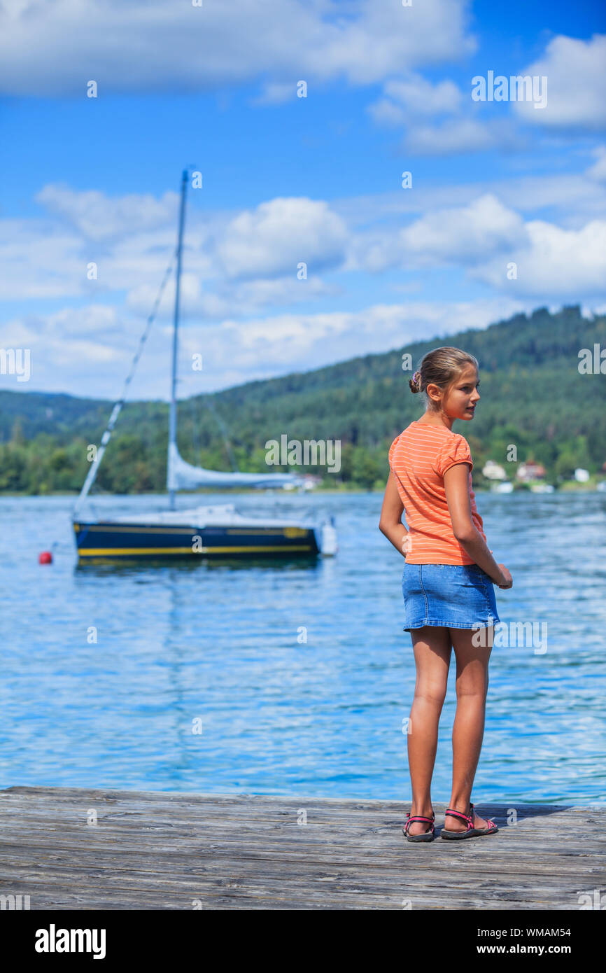 Summer vacation at the lake - happy girl walking on the pier and ...
