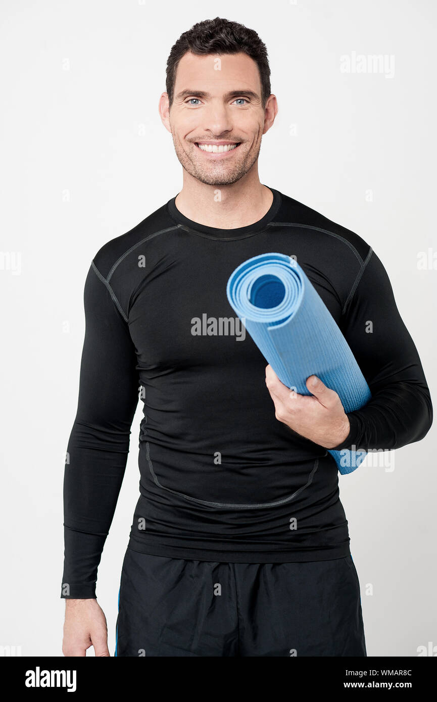 Fitness man holding rolled up exercise mat Stock Photo - Alamy