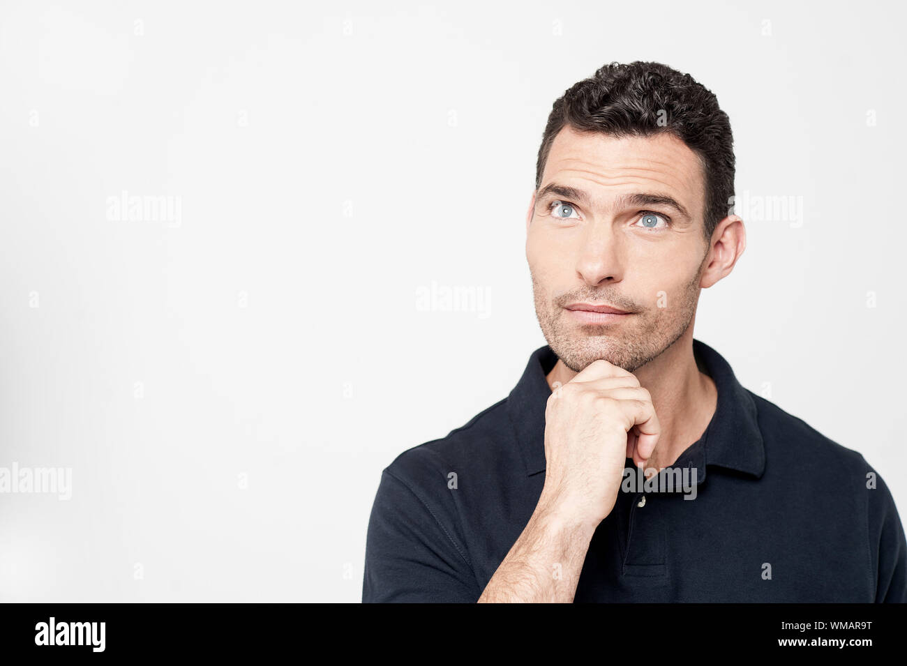 Casual man thinking deeply with hand on chin Stock Photo - Alamy