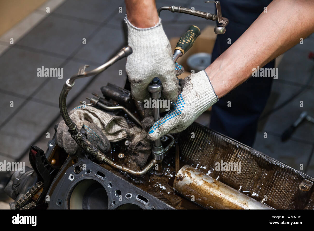 A car repair and maintenance specialist unscrews a bolt with a wrench ...