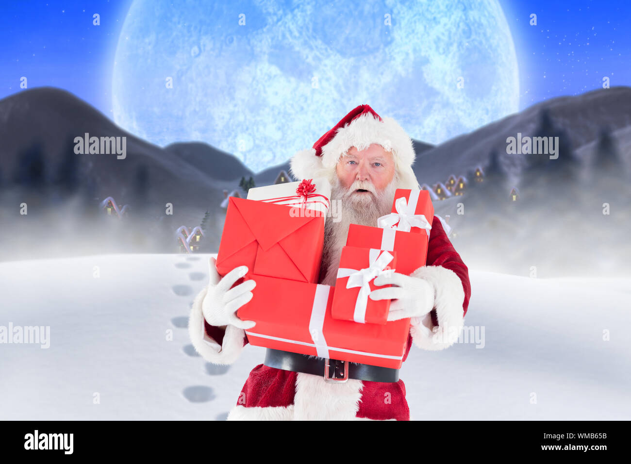 Santa carrying gifts in the snow against christmas village under full ...
