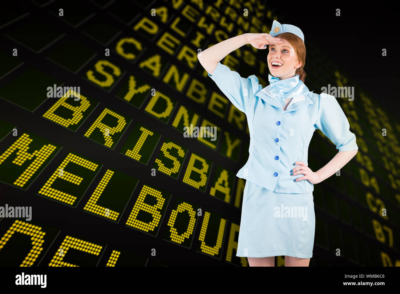 Pretty air hostess looking up against black airport departures board ...