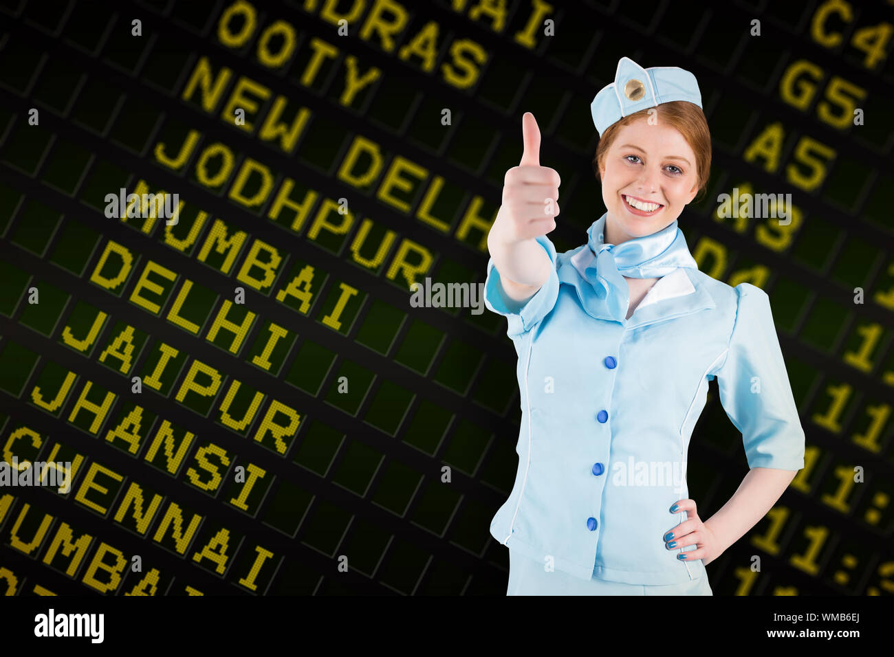 Pretty air hostess with hand on hip against black airport departures ...