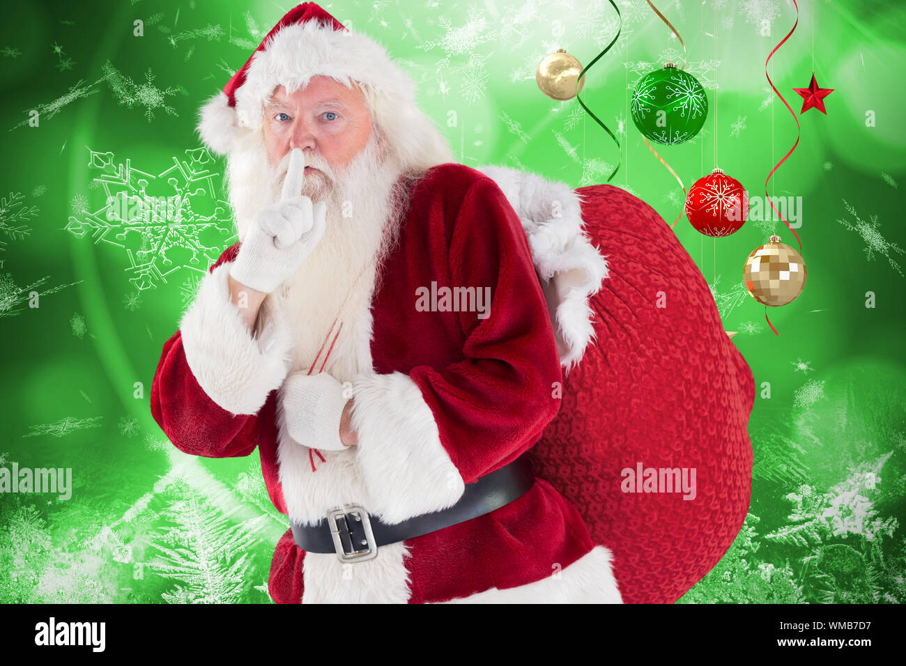 Santa asking for quiet with bag against hanging christmas decorations ...
