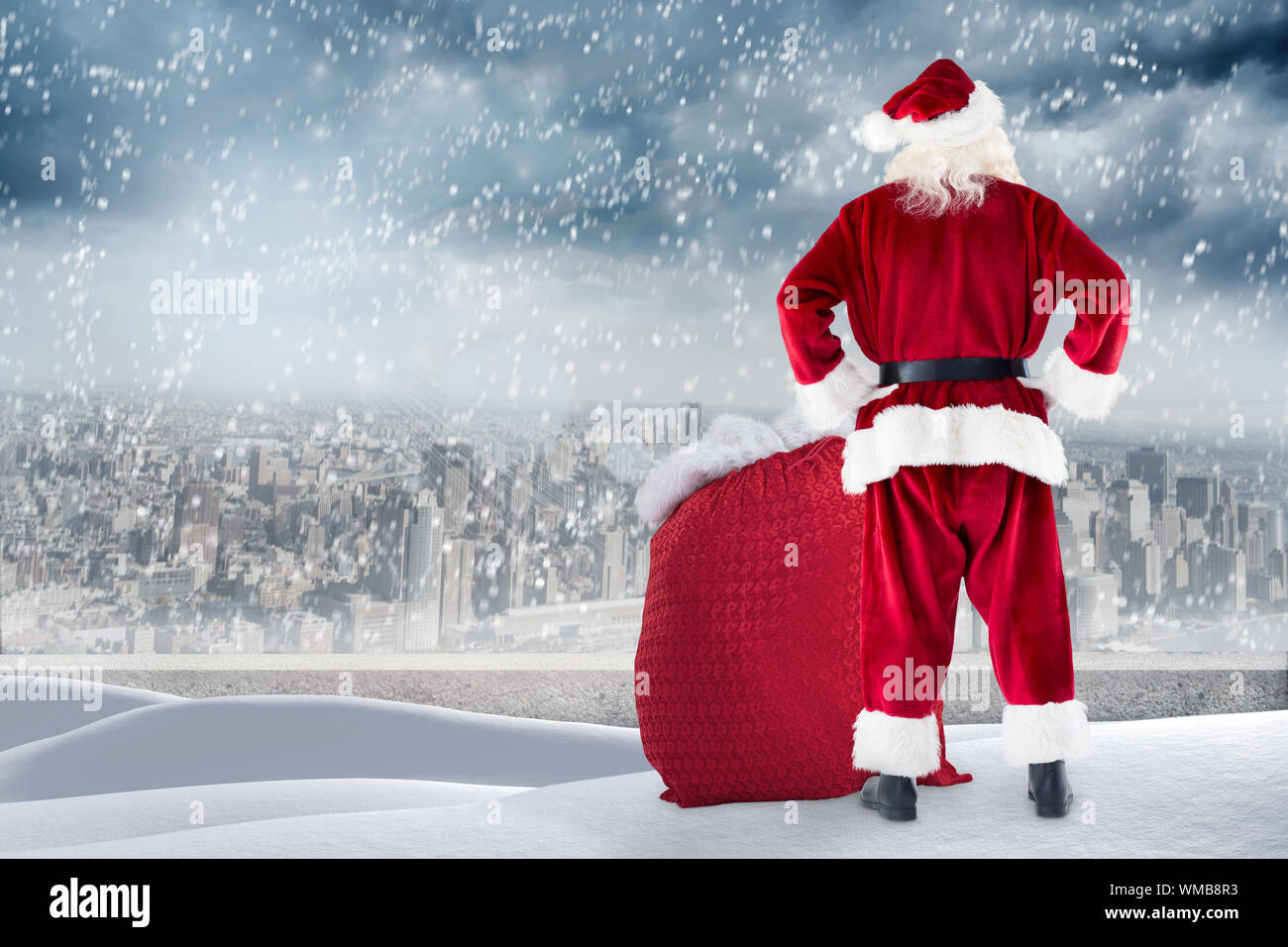 Santa standing on snowy ledge against balcony overlooking city Stock ...