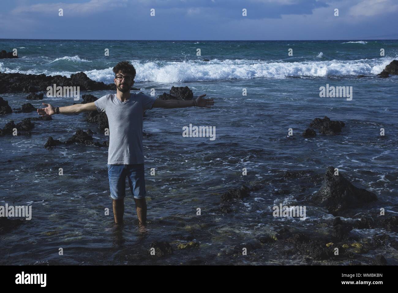 Man With Arms Outstretched Standing On Shore At Beach Stock Photo - Alamy