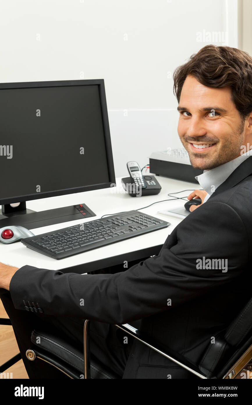 Stylish businessman in a suit sitting at his desk in the office ...