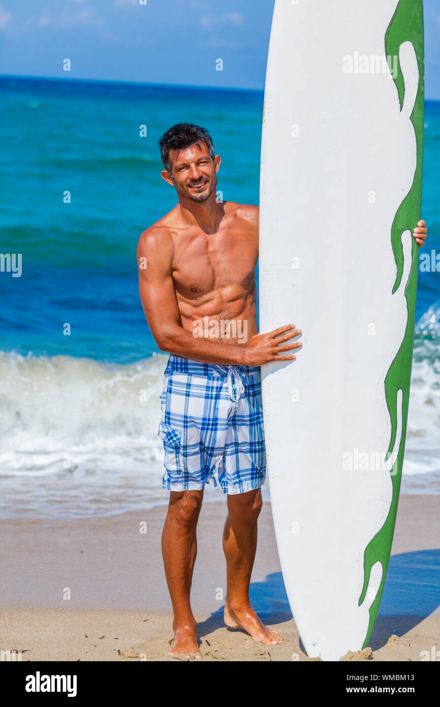 Strong young surf man at the beach with a surfboard Stock Photo - Alamy