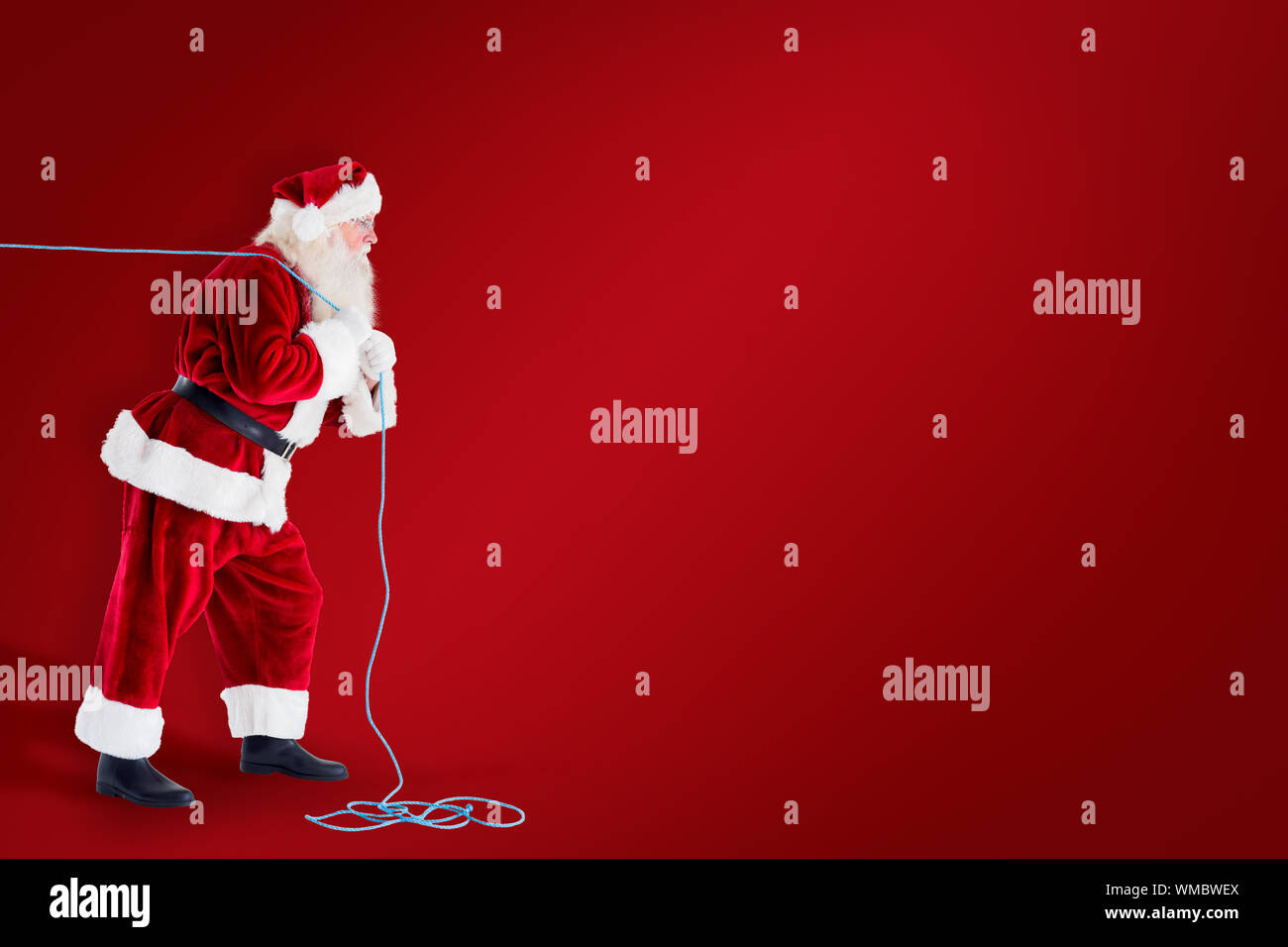 Santa claus pulling rope against red background Stock Photo - Alamy