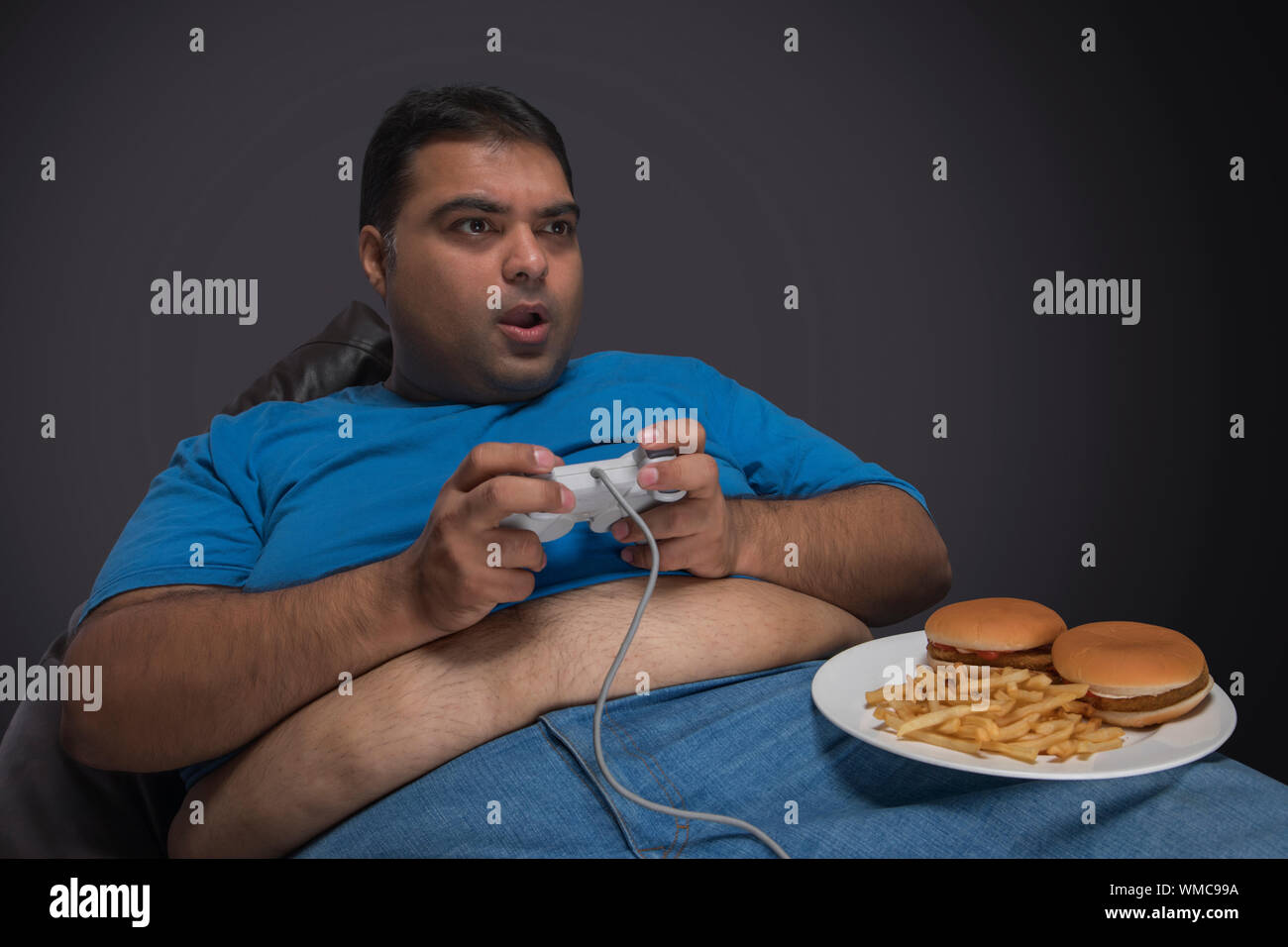 Obese man with belly visible out of his shirt seriously playing video ...