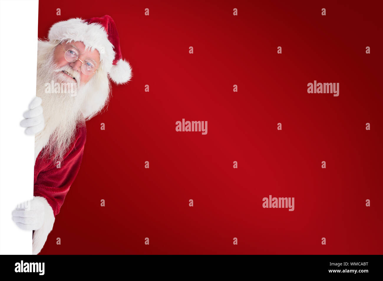 Santa looks out behind a wall against red background Stock Photo - Alamy