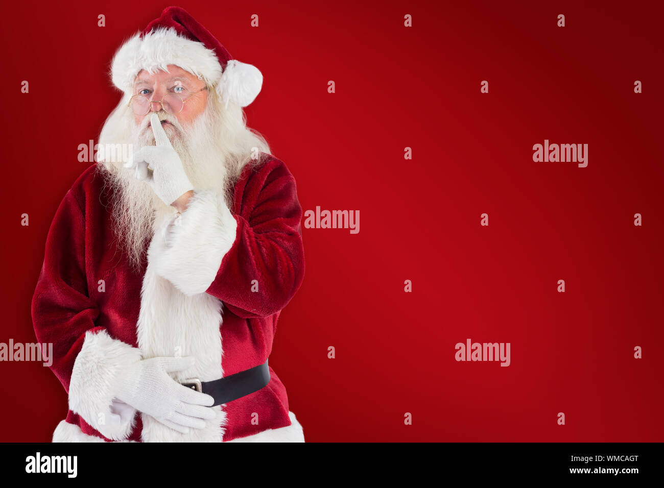 Santa asking for quiet to camera against red background Stock Photo - Alamy