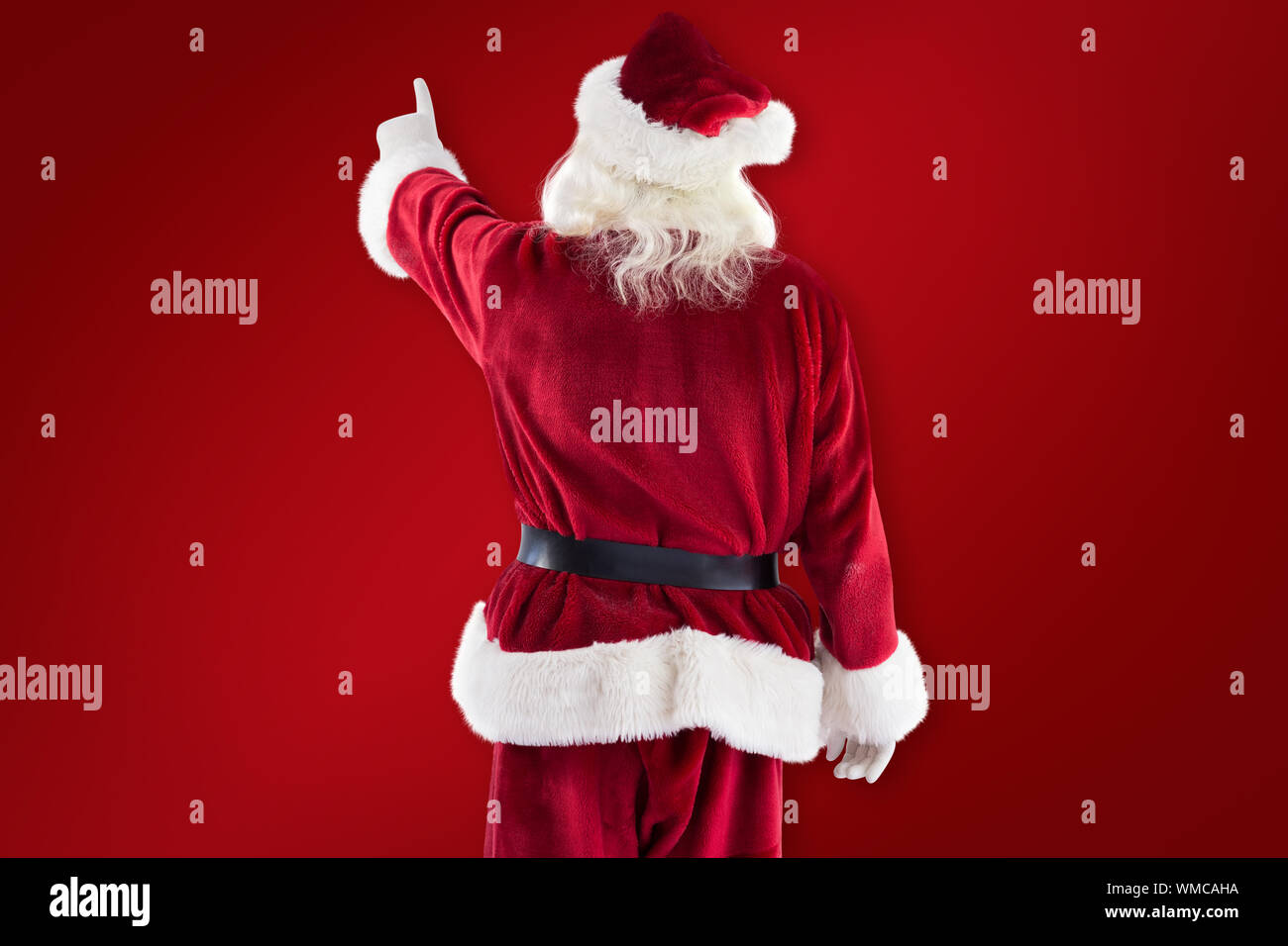 Santa Claus points at something against red background Stock Photo - Alamy