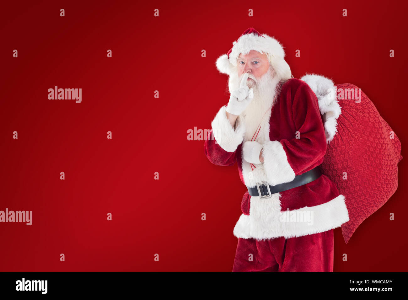 Santa asking for quiet with bag against red background Stock Photo - Alamy