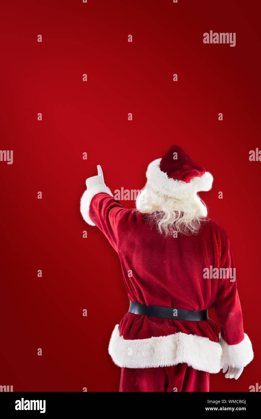 Santa Claus points at something against red background Stock Photo - Alamy