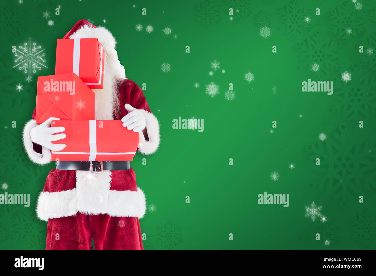 Santa covers his face with presents against green snowflake background ...