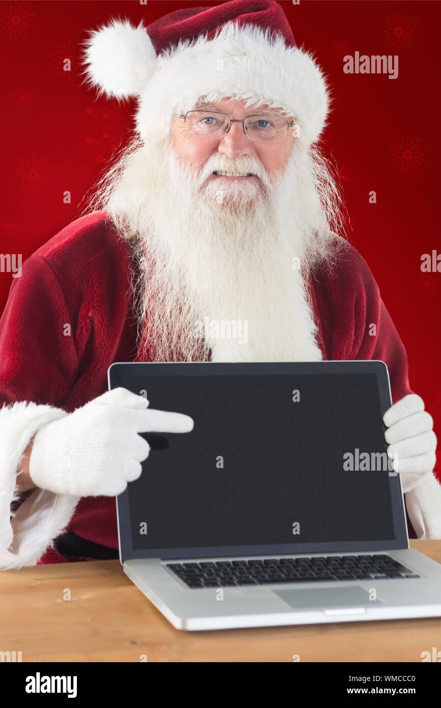 Happy Santa showing laptop screen against red background Stock Photo ...