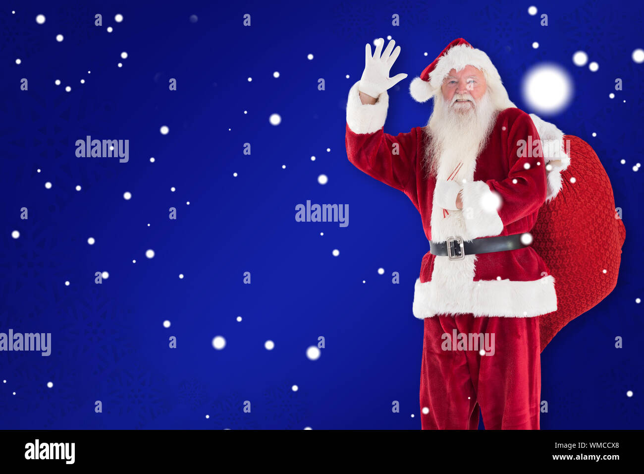 Santa waves to the camera against blue Stock Photo - Alamy