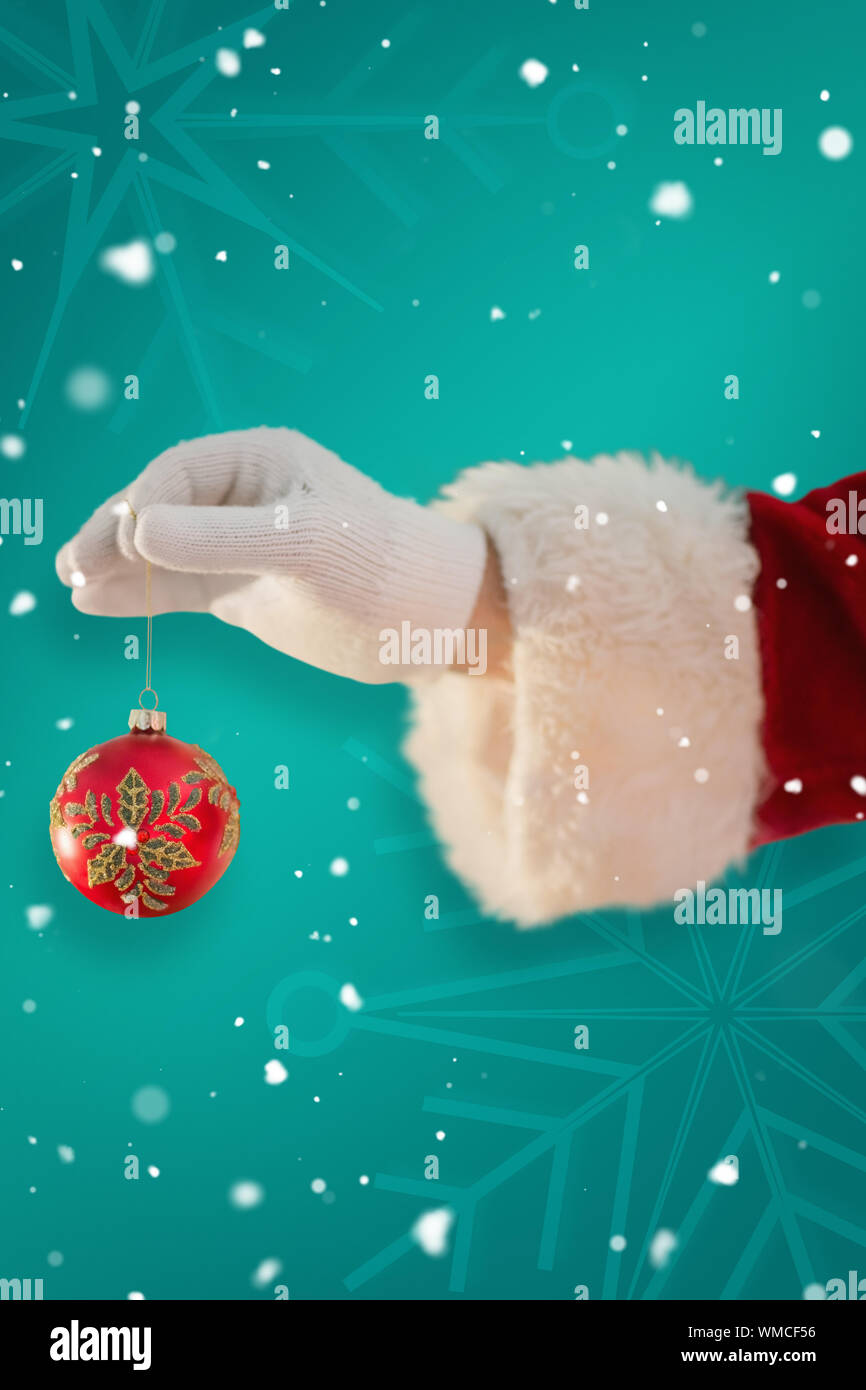 Santas hand is holding a Christmas bulb against green snowflake ...