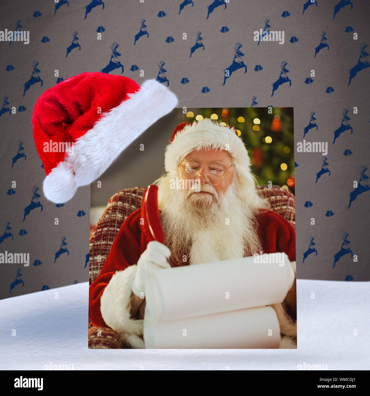 Santa claus writing his list with a quill against grey reindeer pattern ...