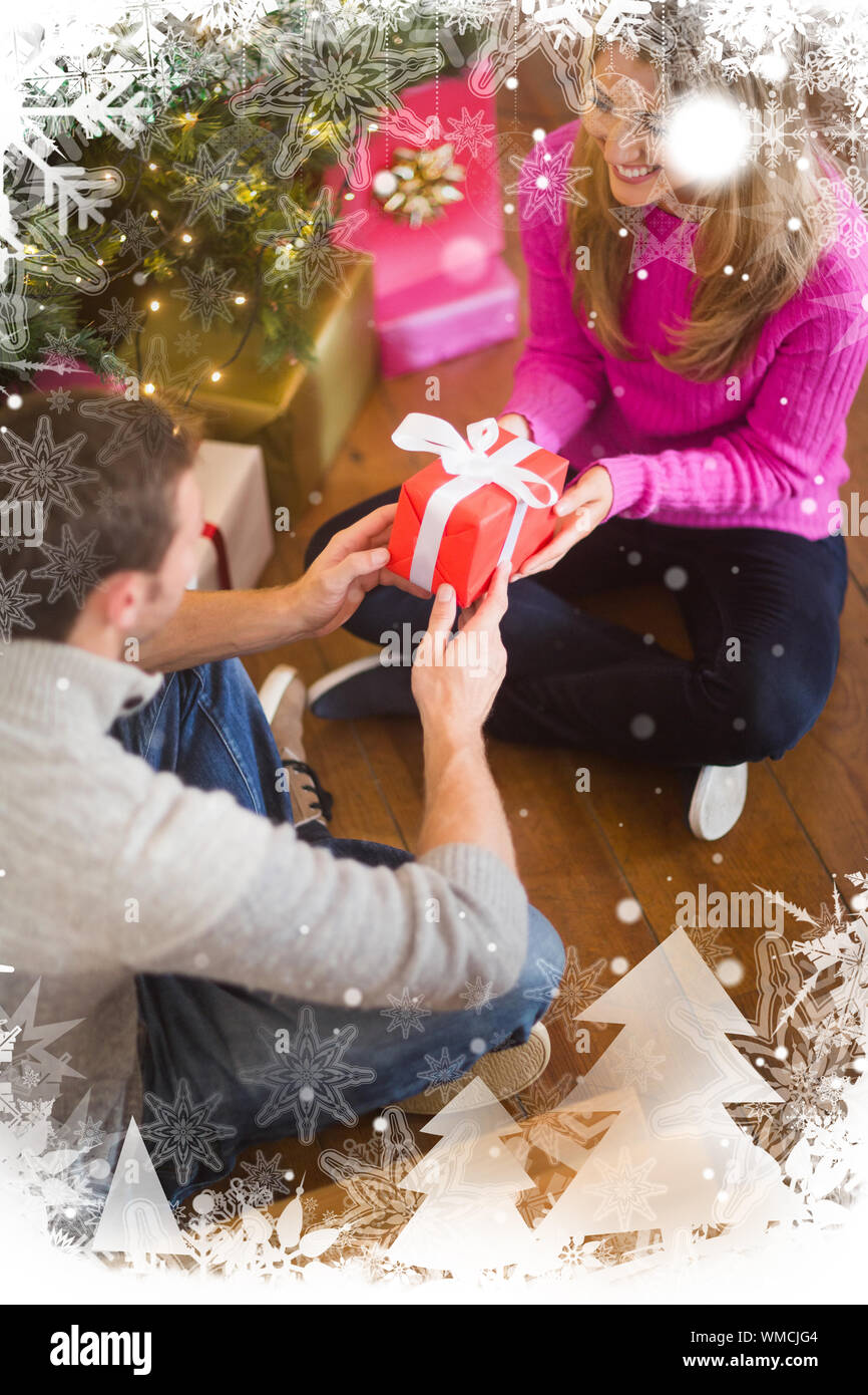 Sitting couple giving each other presents against christmas theme frame ...