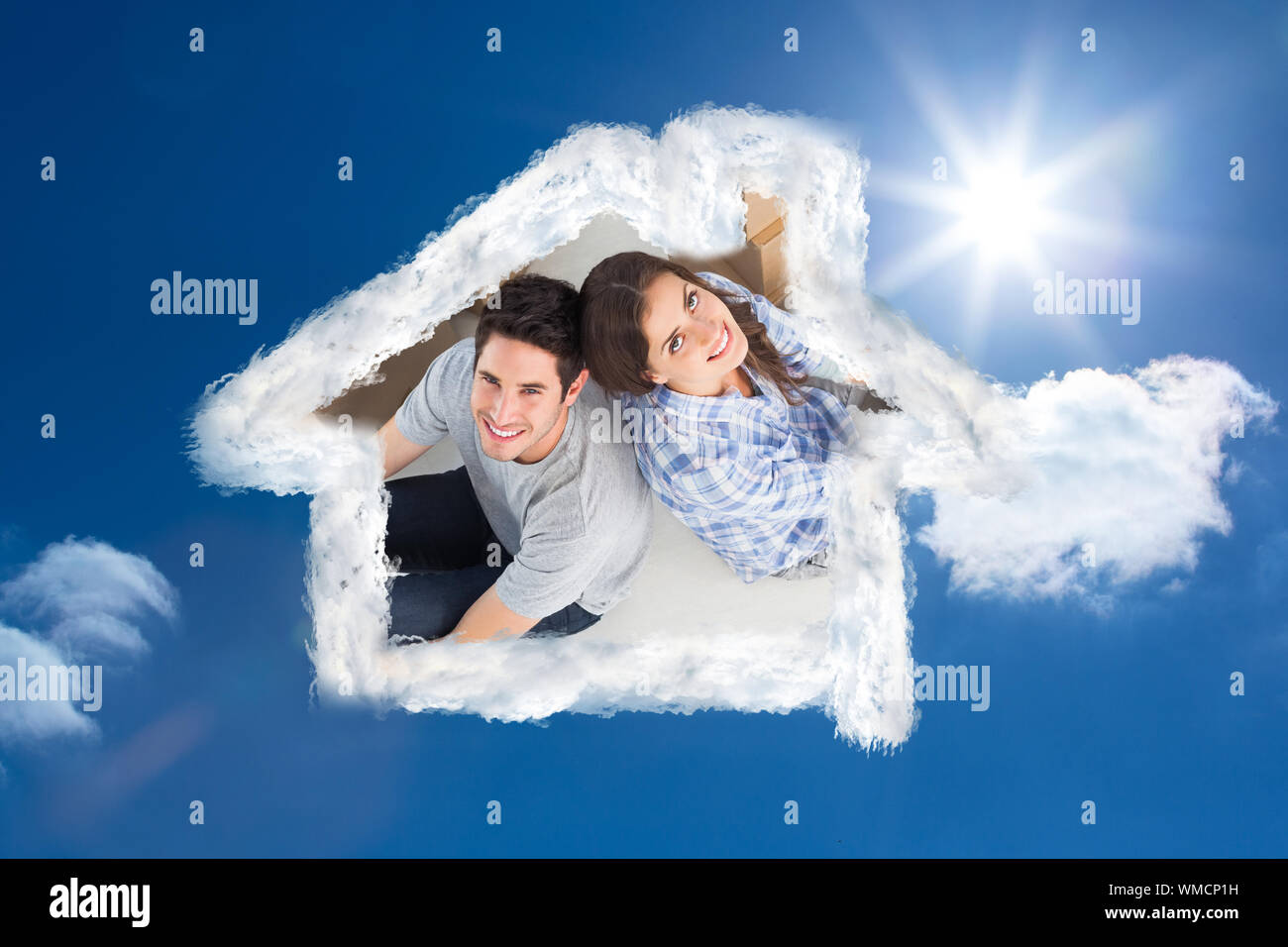 Overview of a happy couple sitting back-to-back against bright blue sky ...