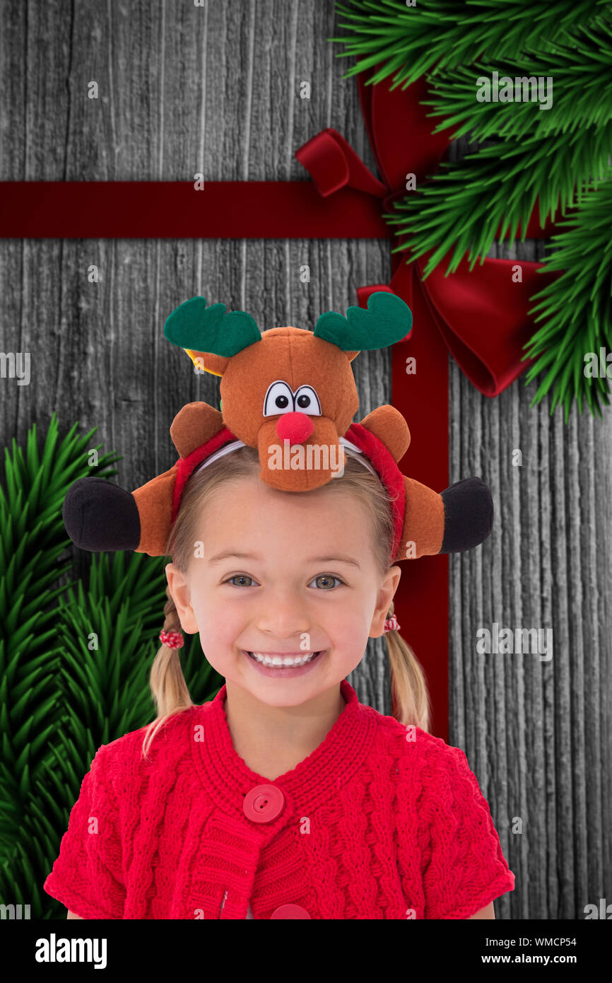 Cute little girl wearing rudolph headband against wood with festive bow ...