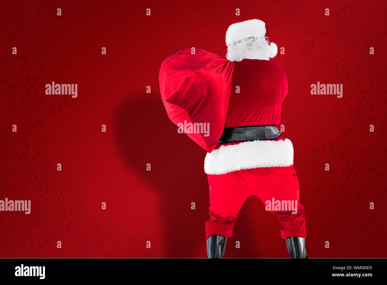 Rear view of santa holding a sack against red snowflake background ...