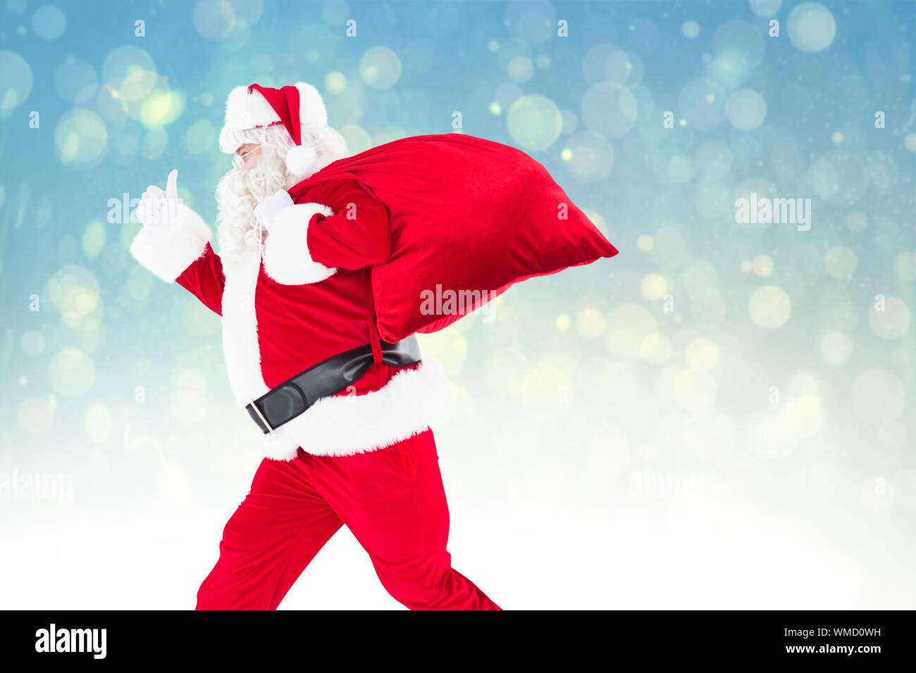 Positive santa with a sack and thumbs up against blue abstract light ...
