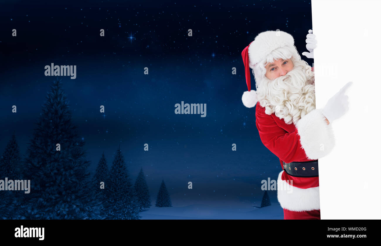 Smiling santa claus pointing poster against night sky over forest Stock ...
