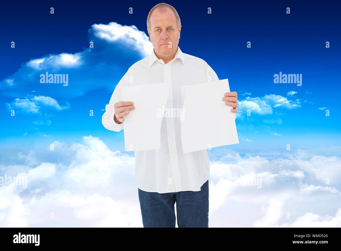 Serious man holding torn sheet of paper against bright blue sky with ...