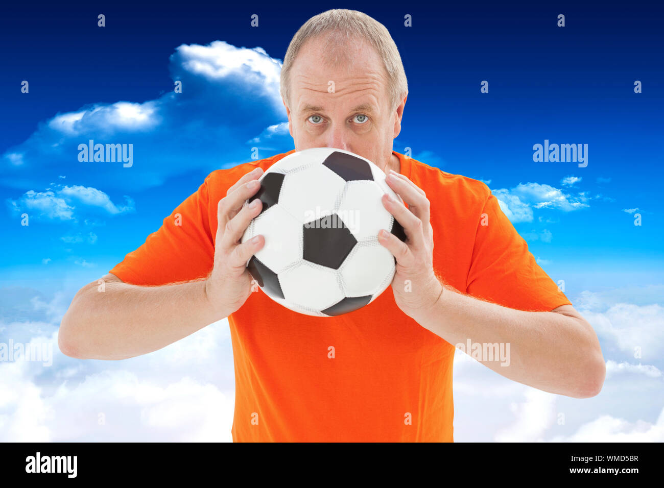 Nervous football fan holding ball against bright blue sky with clouds ...