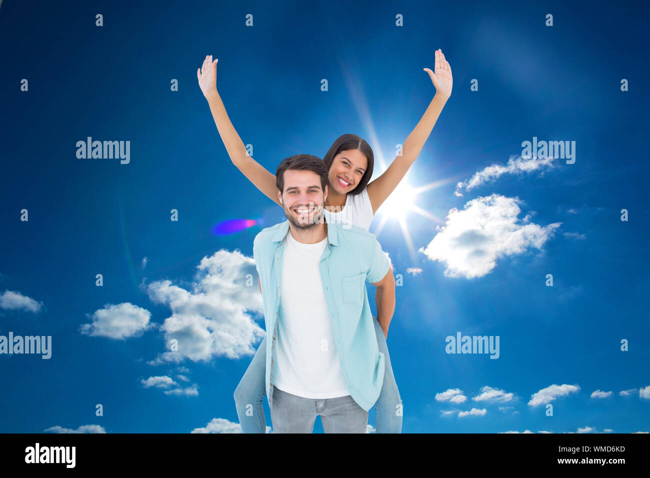 Happy casual man giving pretty girlfriend piggy back against cloudy sky ...
