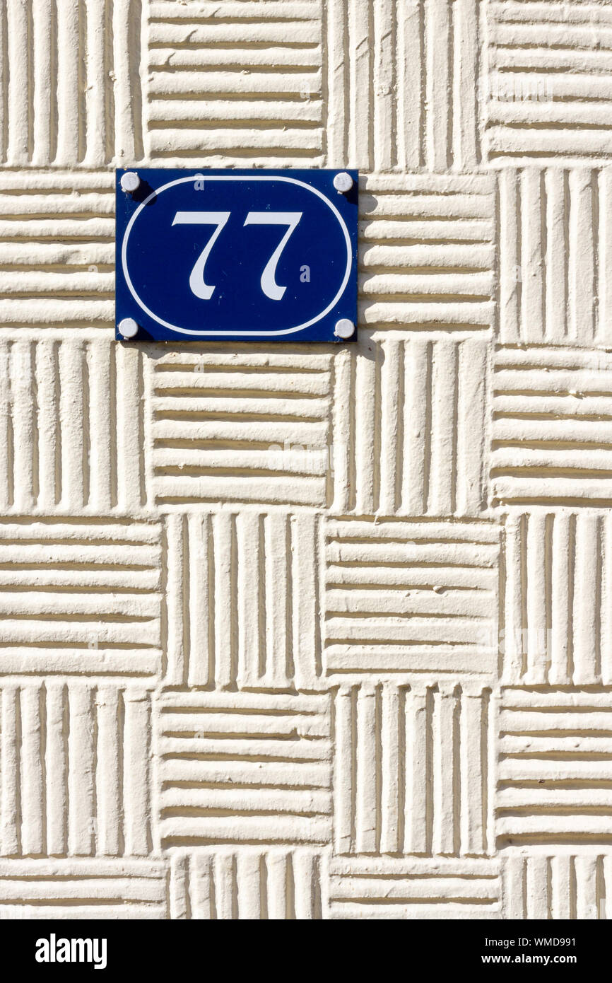 House number 77 on a structured plaster wall with square pattern of ...