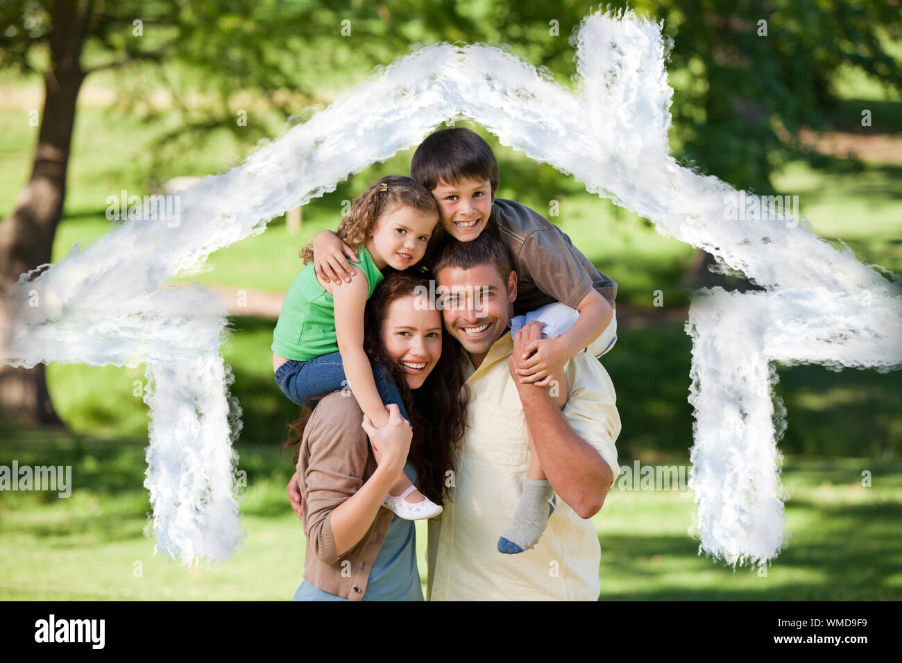 Parents giving children a piggyback against house outline in clouds ...