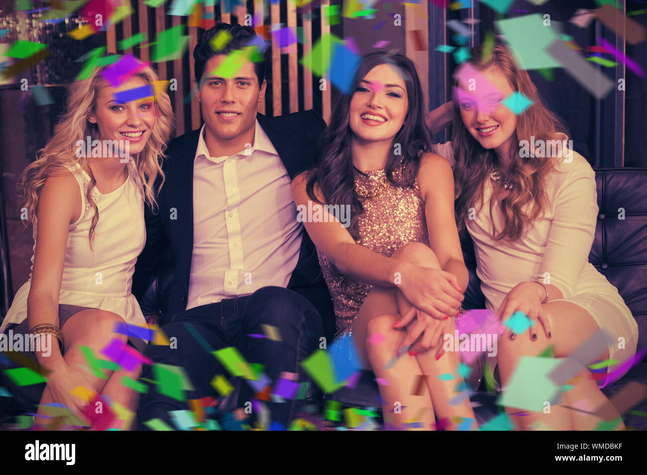 Happy friends smiling at camera against flying colours Stock Photo - Alamy