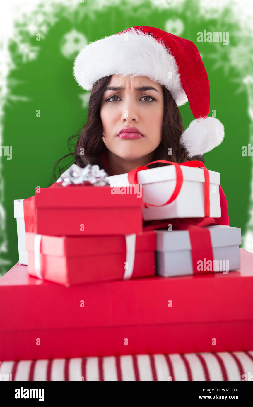 Confused brunette holding pile of gifts against fir trees with snow ...