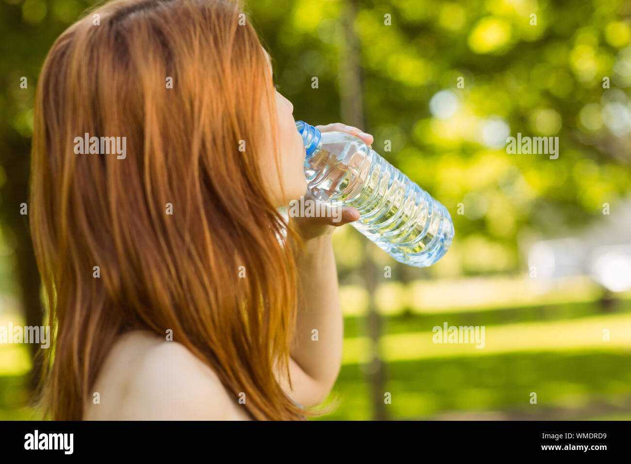 Pretty redhead drinking water in park at sunshine Stock Photo - Alamy