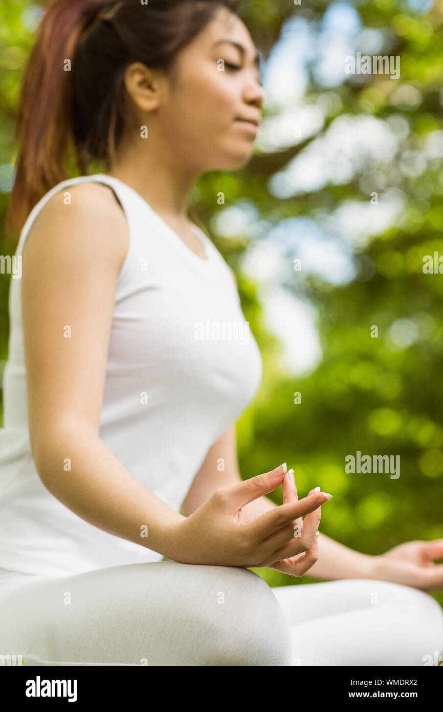 Side view of healthy and beautiful young woman sitting in lotus pose at ...
