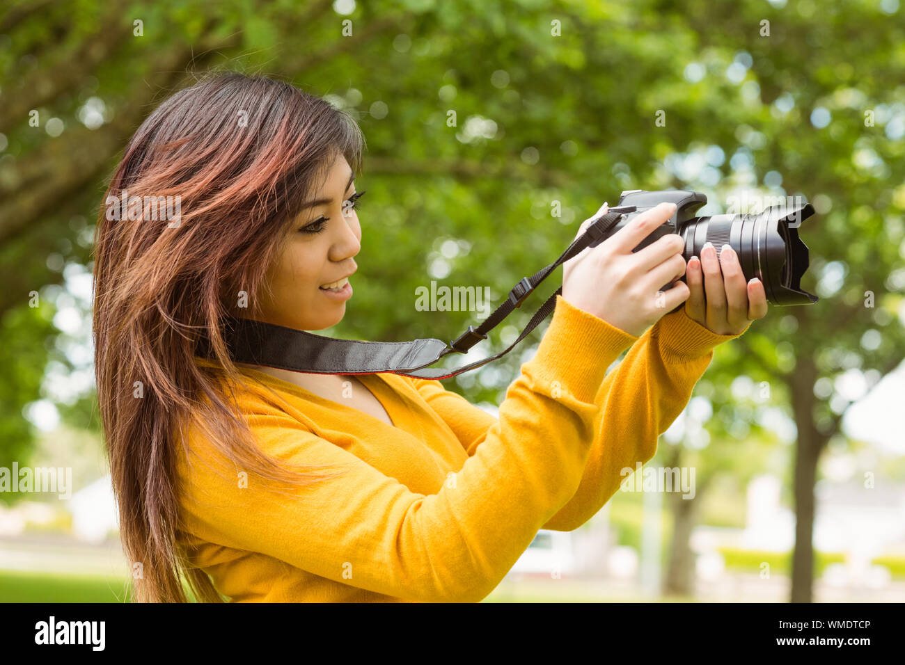 Side view of beautiful female photographer at the park Stock Photo - Alamy