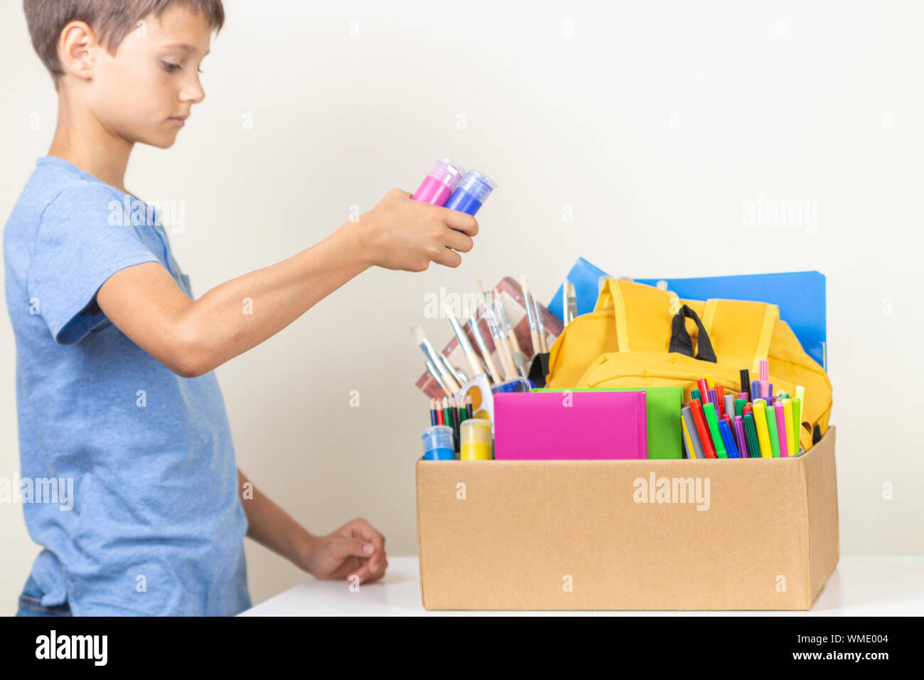 Donation concept. Kid preparing donate box with books, pencils and ...
