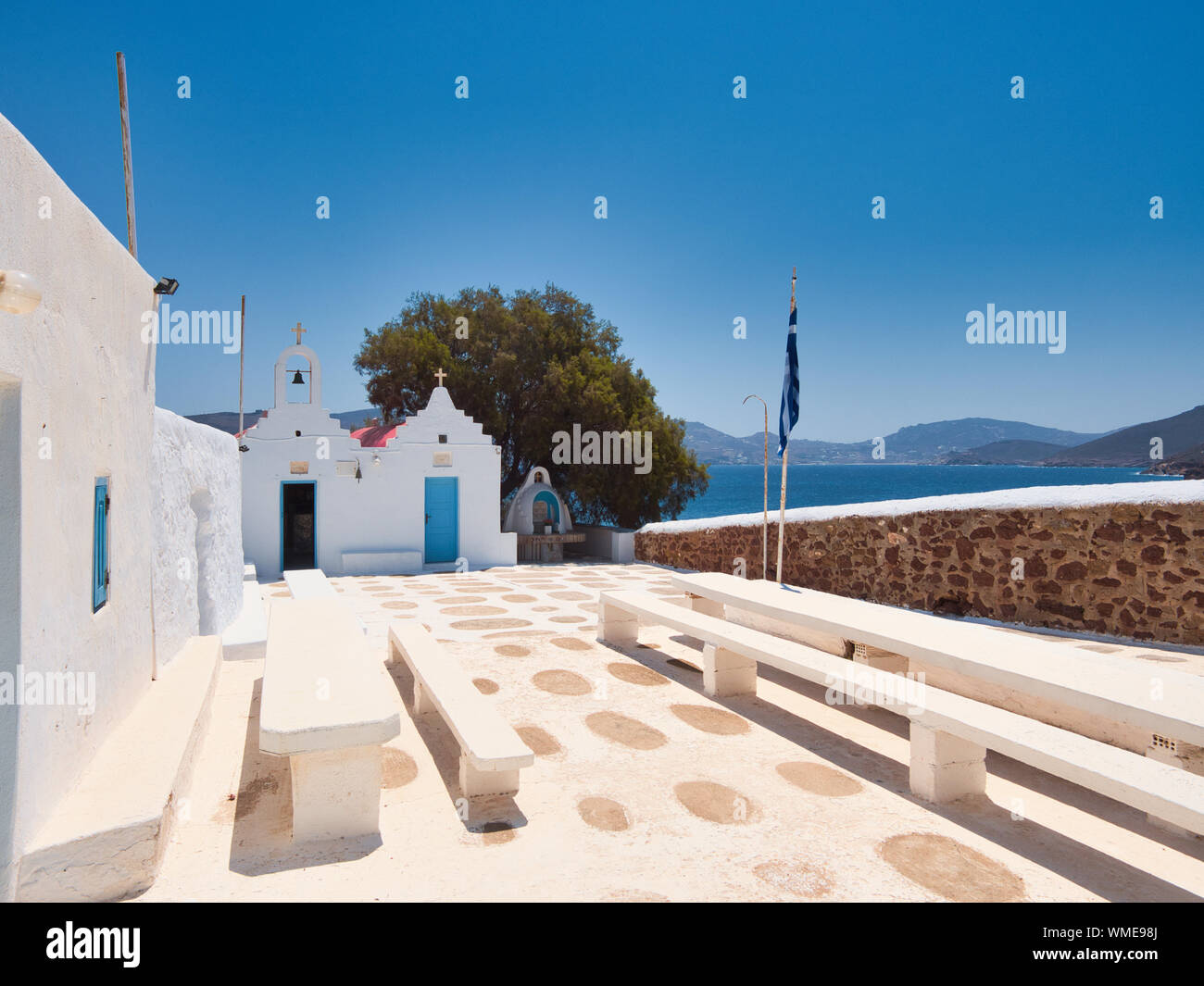 Empty light terrace of old monastery with stone benches and white walls ...