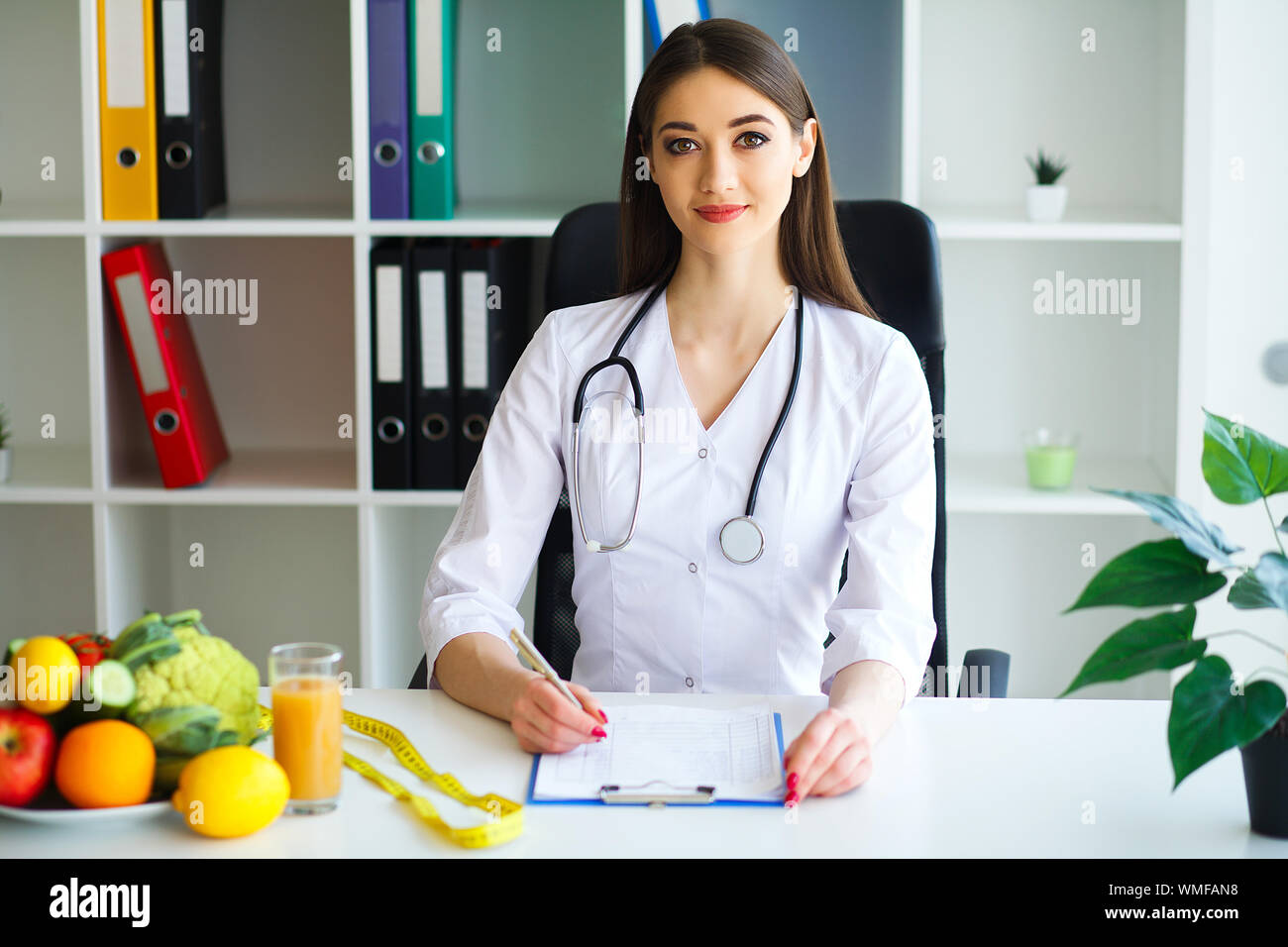 The Doctor Begins to Write a Diet Plan. Beautiful Young Dietitian ...