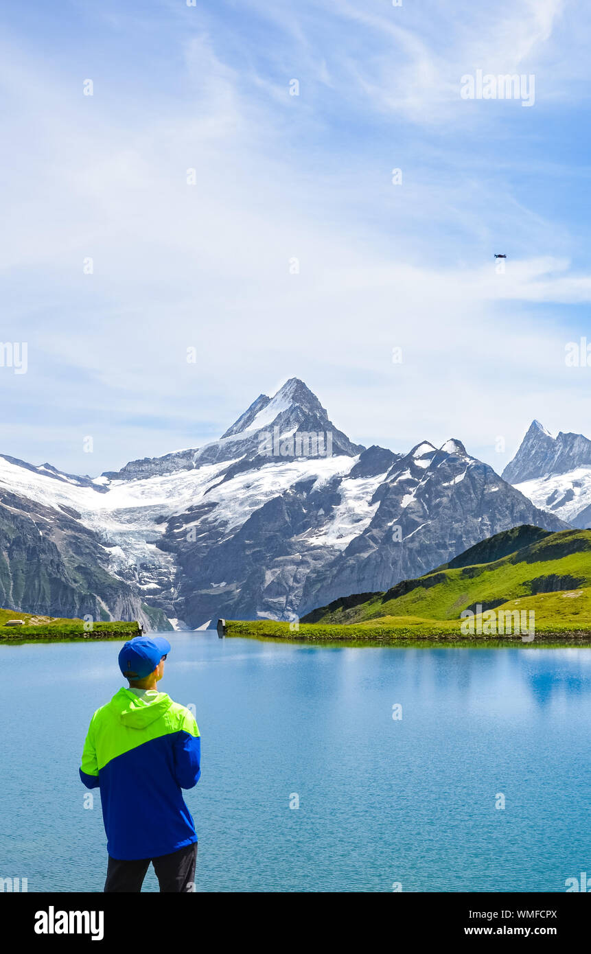 Young man operating the flying drone over amazing Bachalpsee in the ...