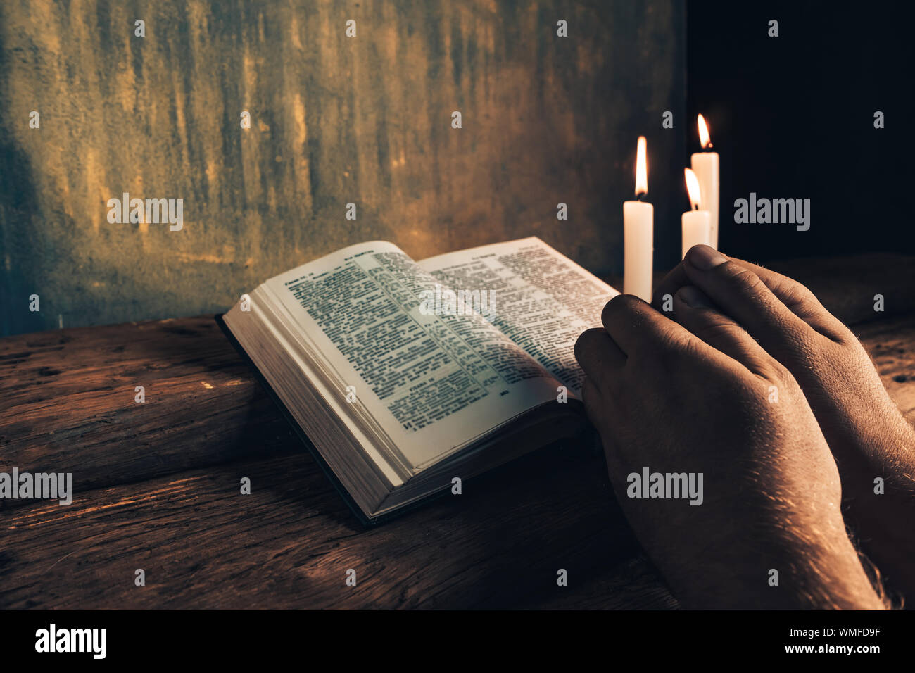 Close up man sitting at a table reading the Bible on a old oak wooden ...