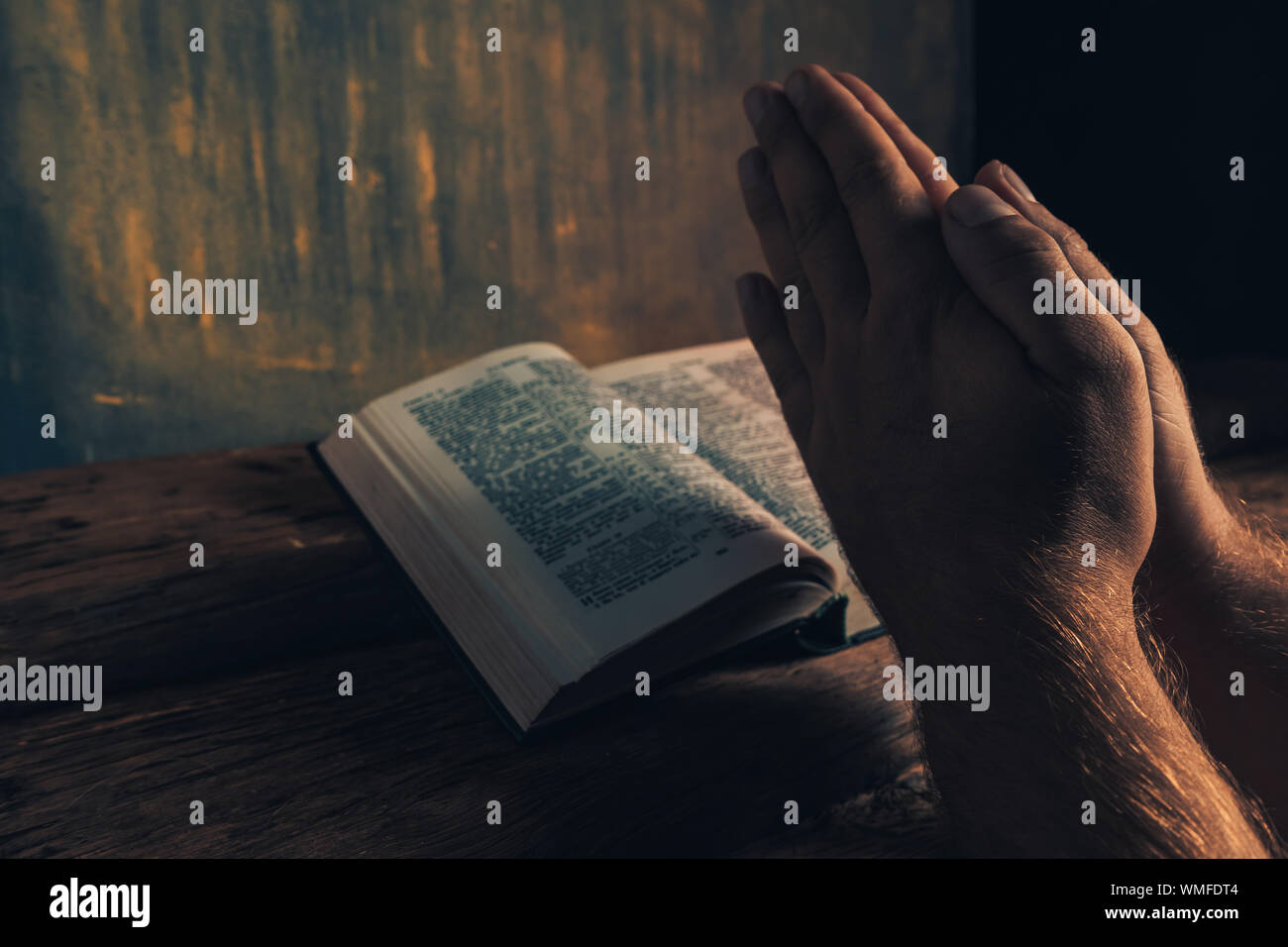 Close up man sitting at a table reading the Bible on a old oak wooden ...
