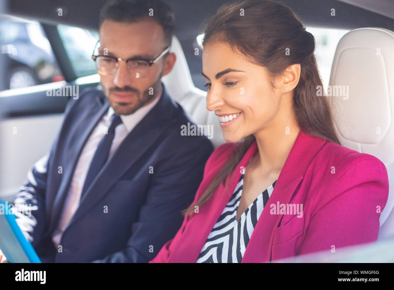 Helpful wife smiling while sitting near husband in the car Stock Photo ...